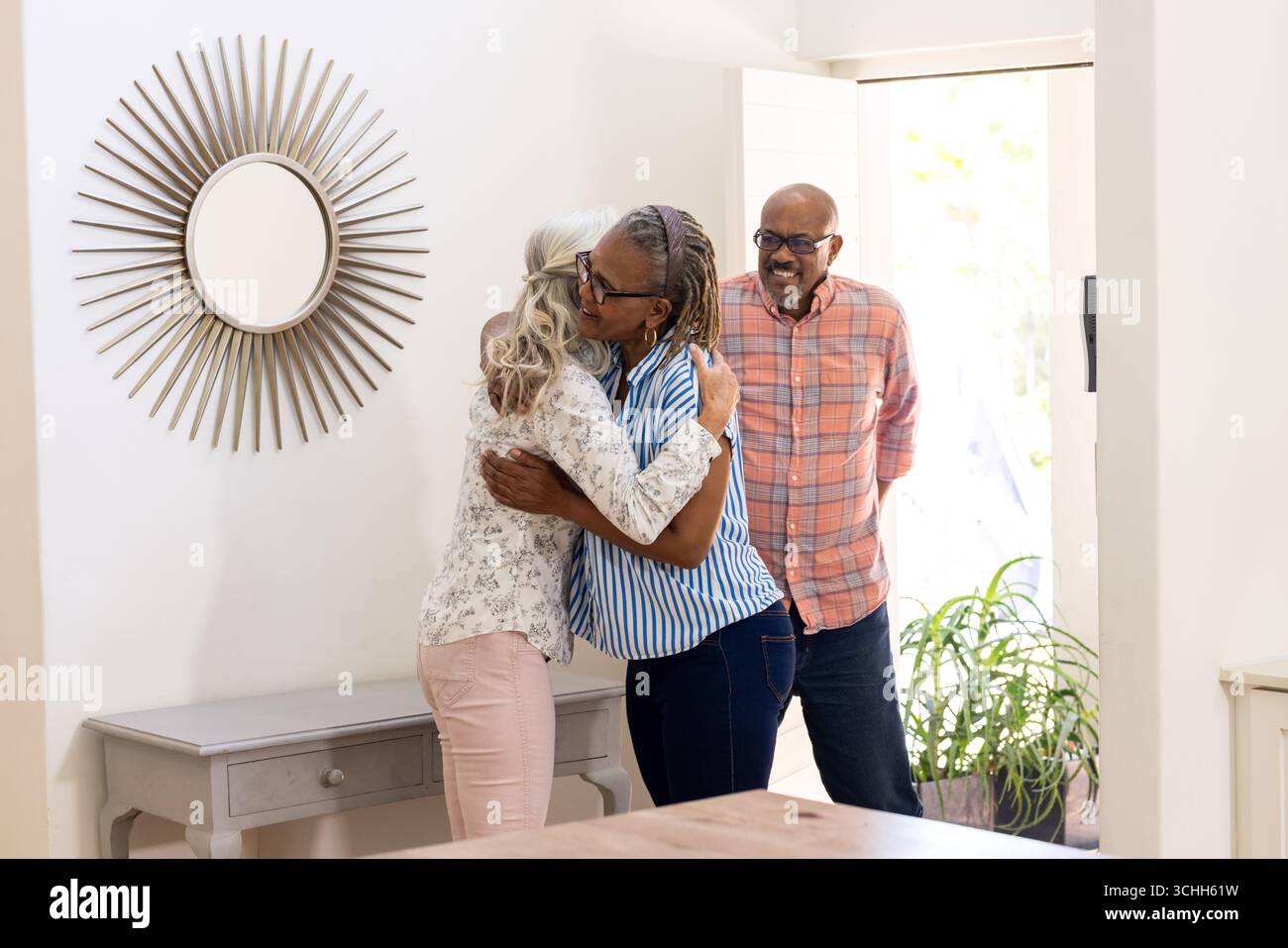 Senior diverse friends greeting with warm hugs at home, sharing joyful ...