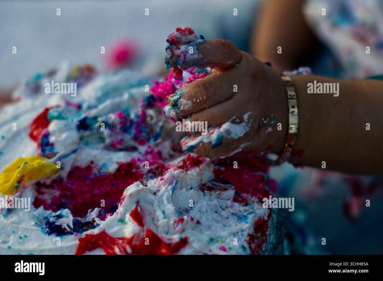 A baby's hand on a cake, messing it up with frosting all on the hand ...