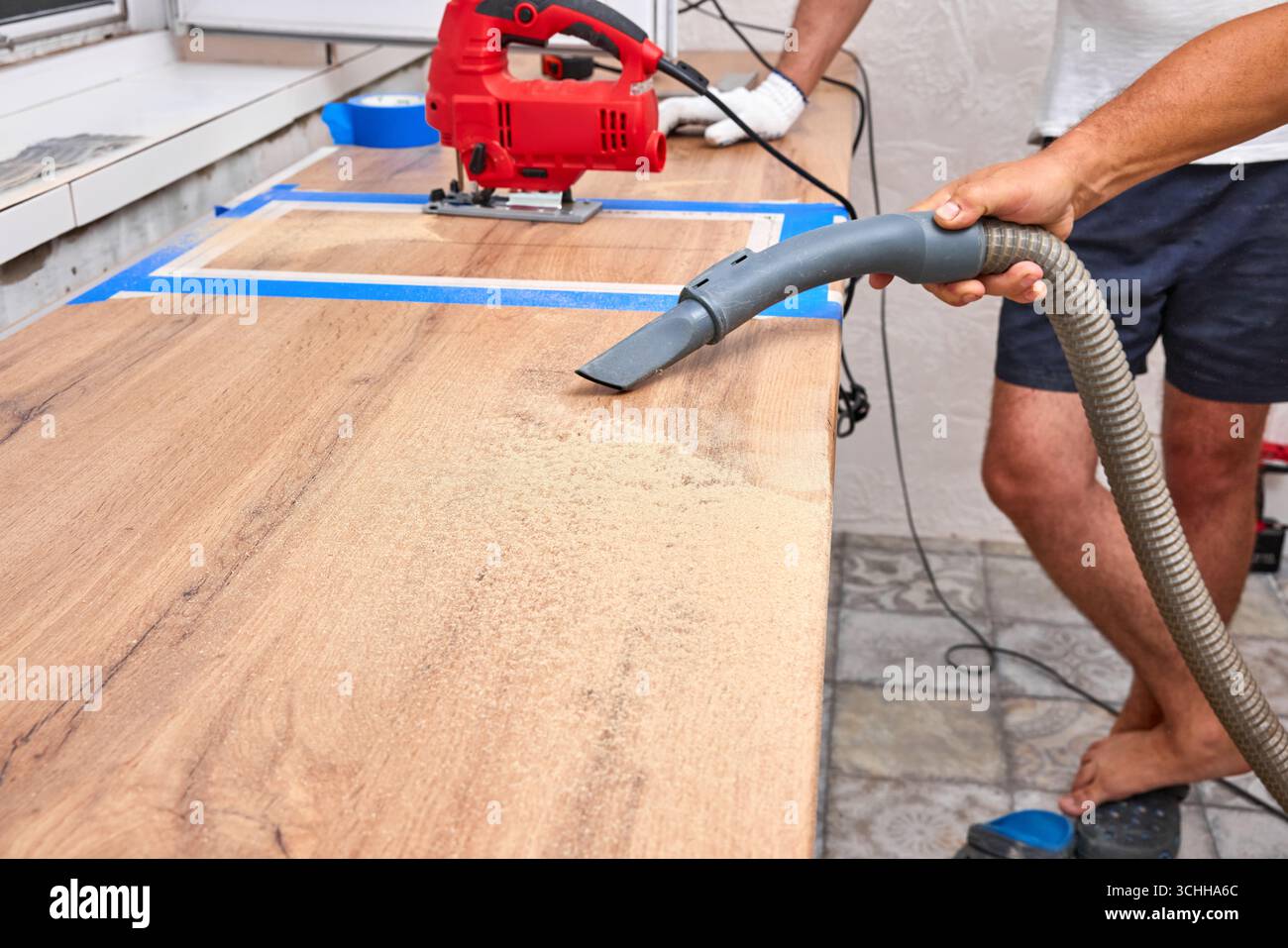 Worker man vacuums new kitchen after cutting hole for the sink in the ...