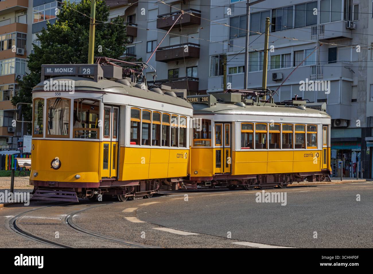Two classic yellow trams, both on the Tram 28 route, are parked on a ...