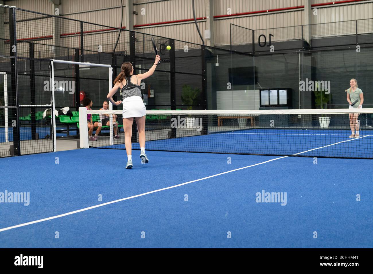 Diverse female friends playing padel tennis inside sports facility with ...