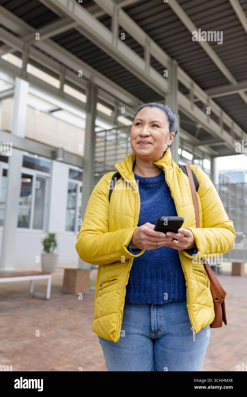 Woman in yellow jacket on walkway under metal canopy checking ...