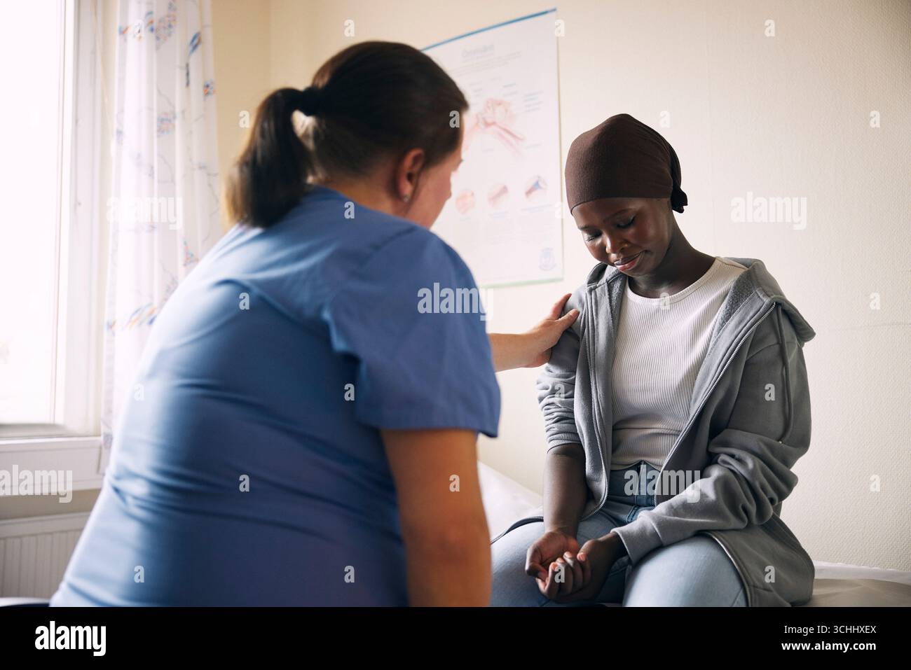 Female healthcare worker consoling sad girl in examination room at ...