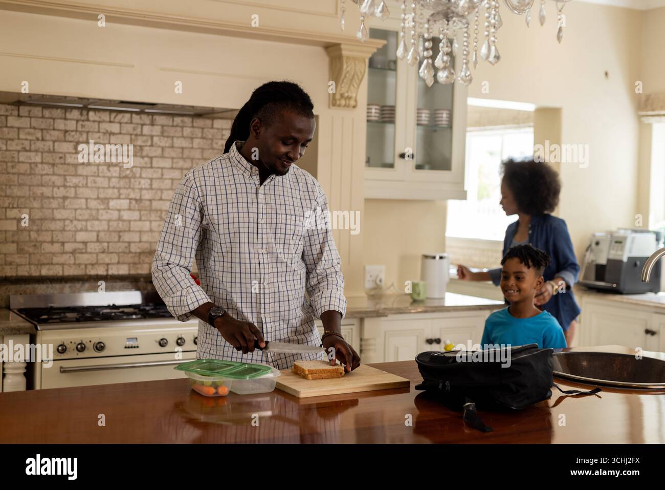 Father preparing lunch in kitchen while mother and son enjoy morning ...