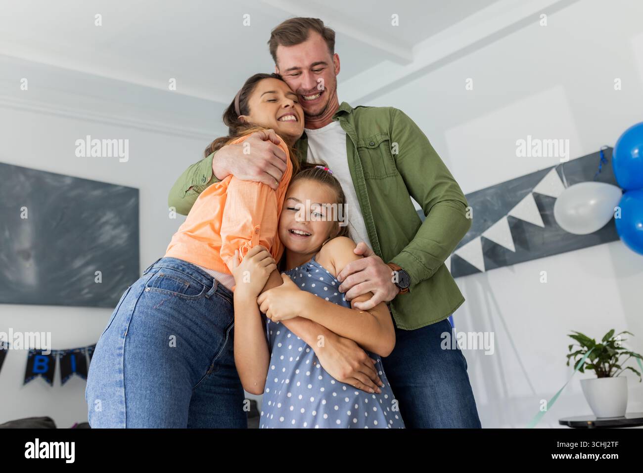 Family celebrating birthday at home, hugging joyfully with balloons and ...