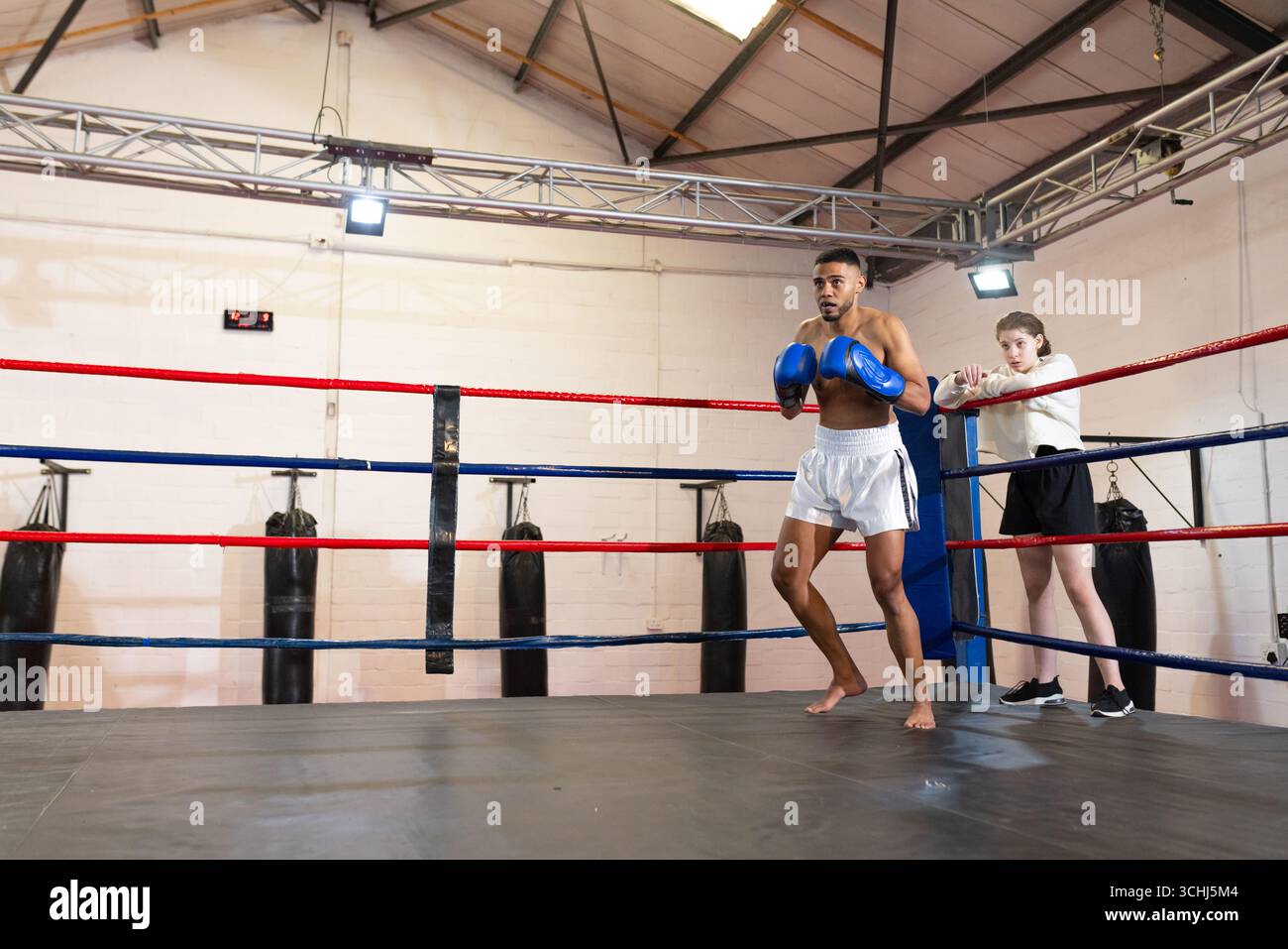 Teenage female coach guiding male trainee practicing boxing in boxing ...