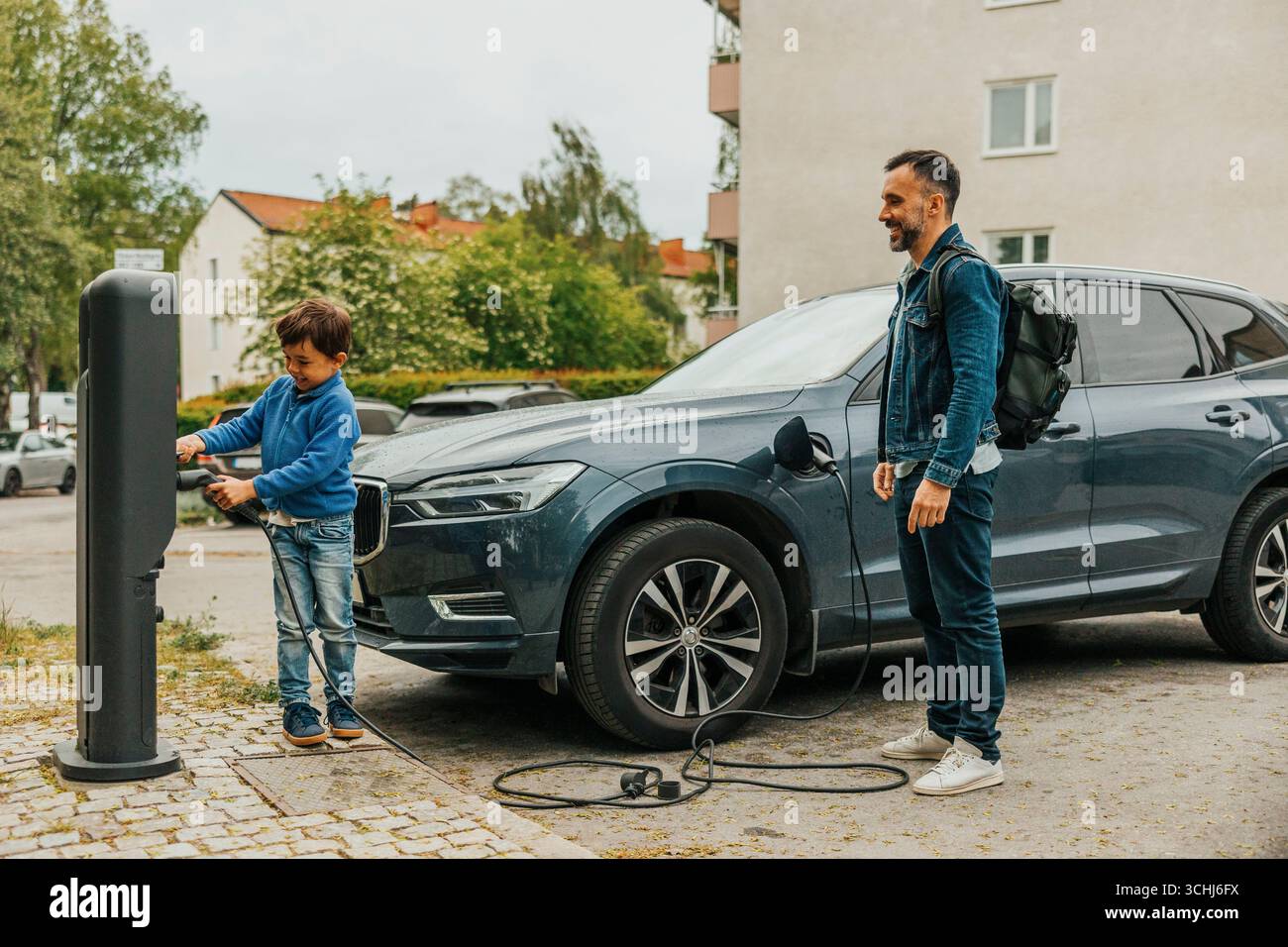 Father with son learning to charge electric car at station Stock Photo ...