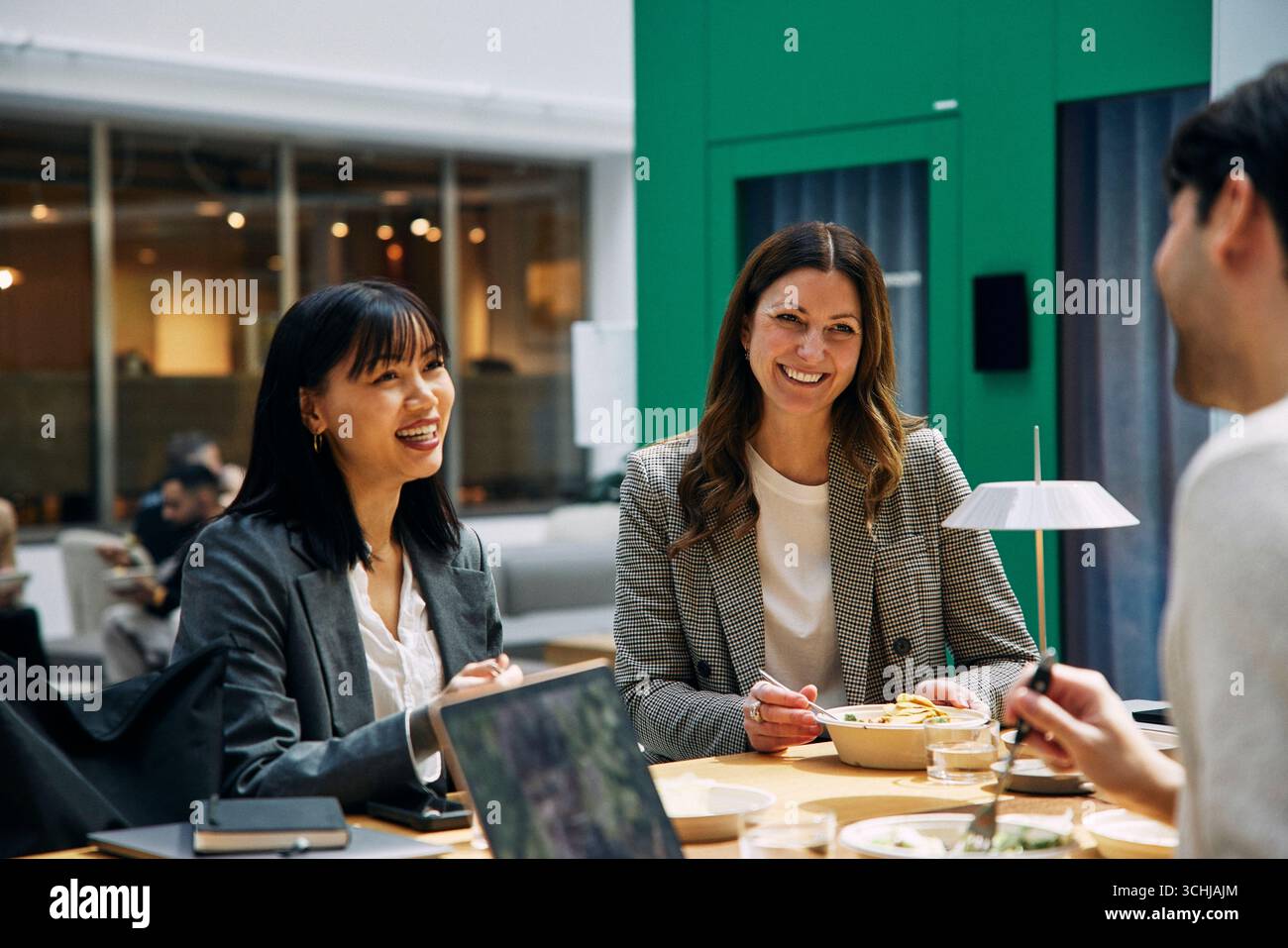 Happy female business experts talking with male coworker during lunch ...