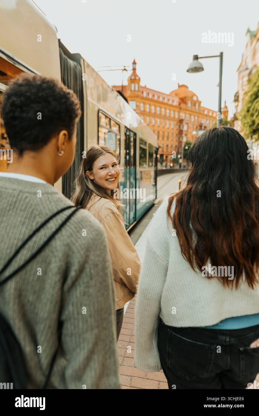 Smiling young woman looking over shoulder while talking with male ...