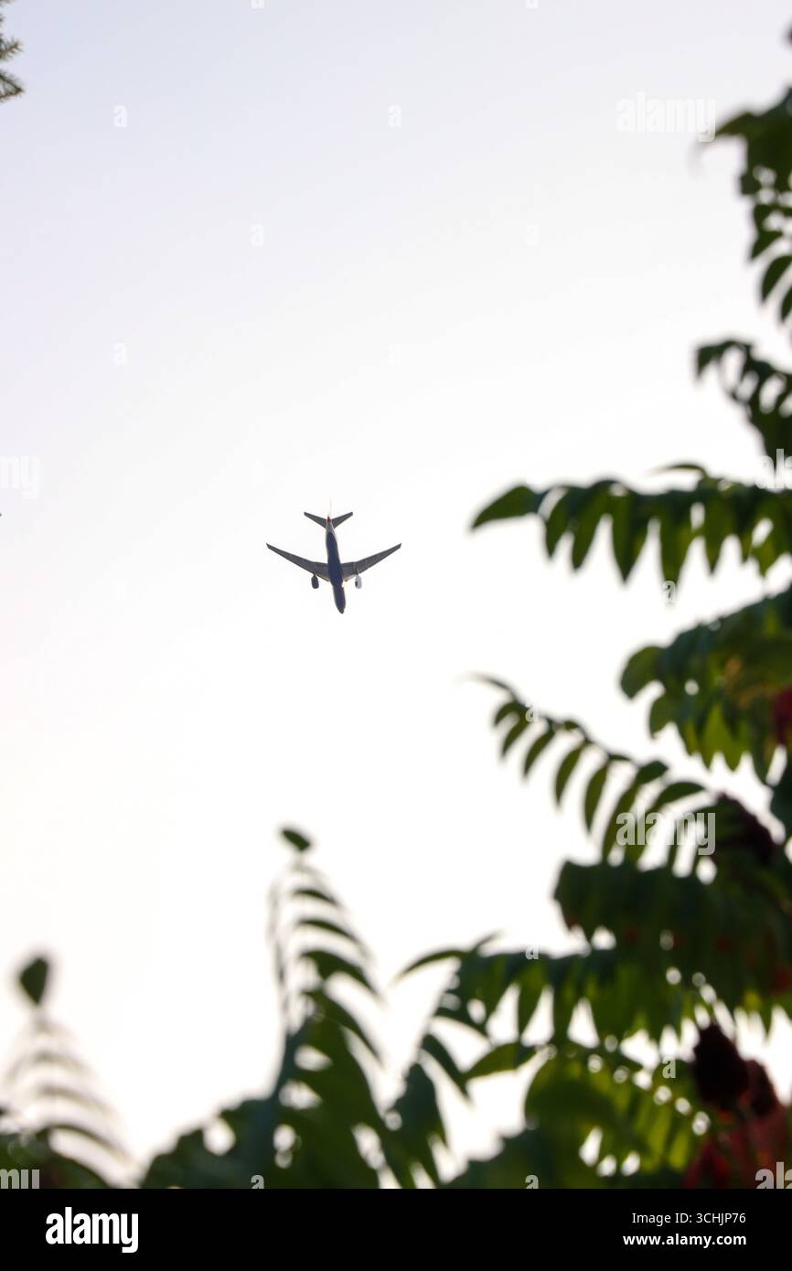 Passenger airplane captured from below, flying across a clear blue sky ...
