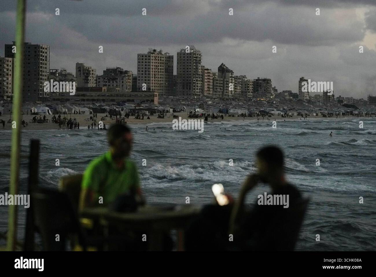 Palestinians spend time at the seafront next to a tent camp in the Gaza ...