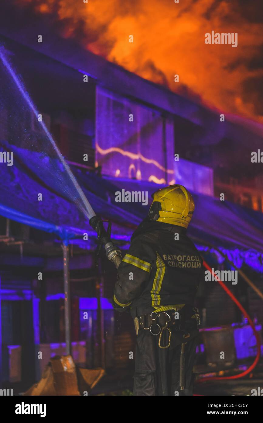 Firefighters in full gear extinguishing a large blaze. Thick smoke and ...