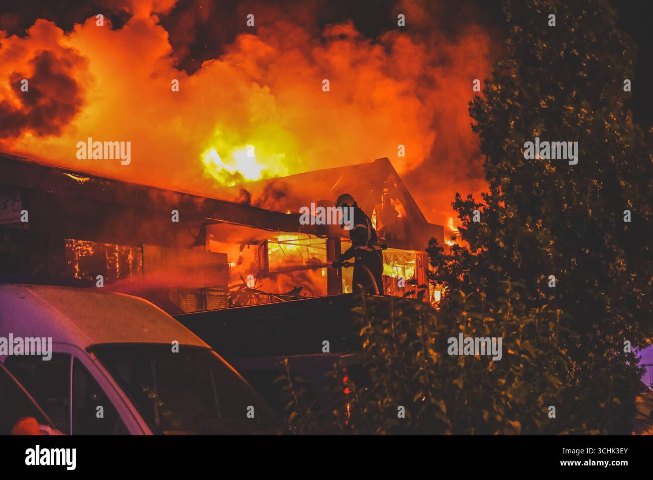 Firefighters in full gear extinguishing a large blaze. Thick smoke and ...
