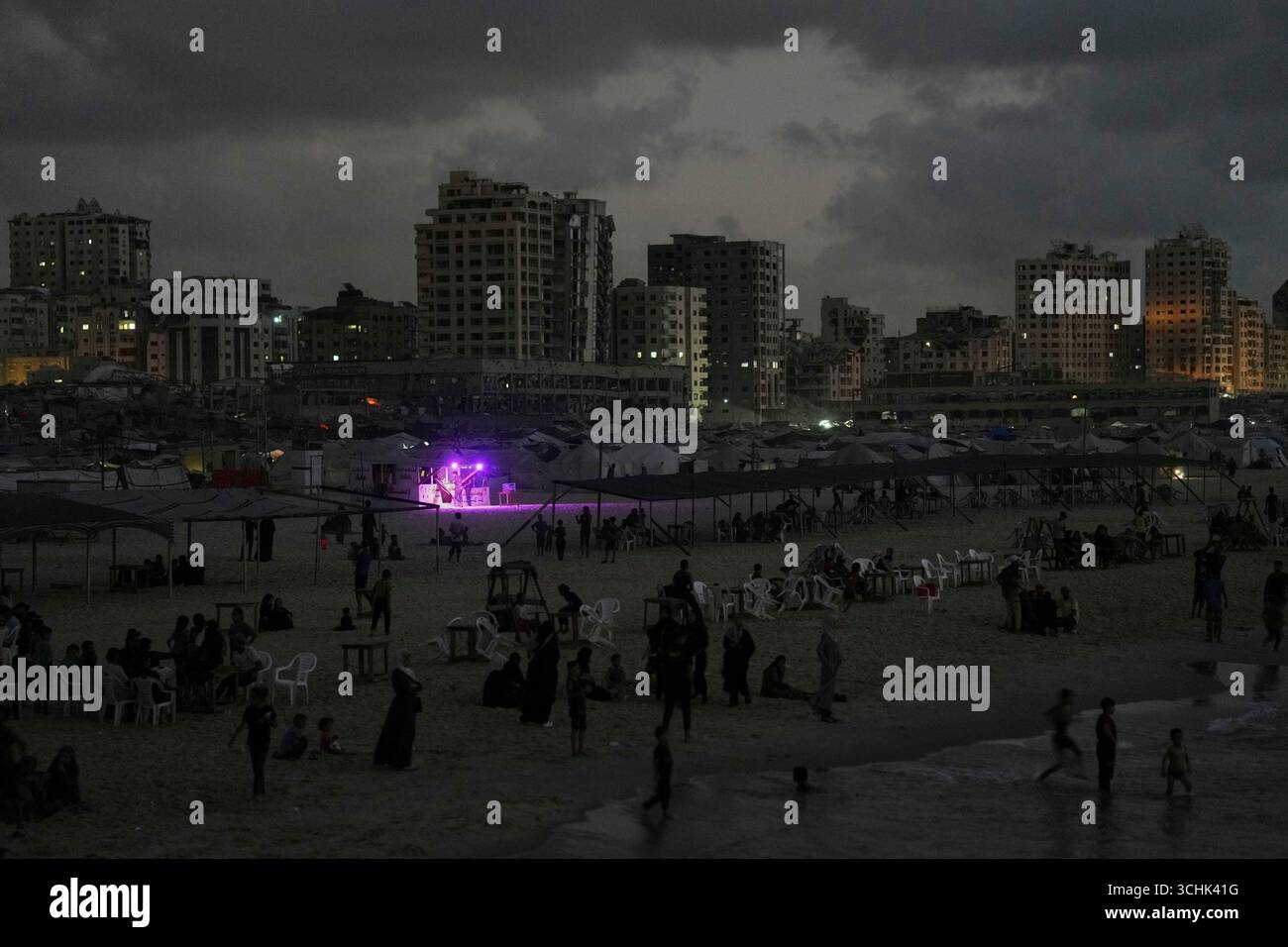 An illuminated food stand stands out as Palestinians cool off in the ...