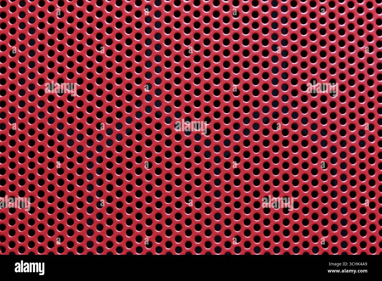 This close-up image showcases a vibrant red perforated metal surface ...