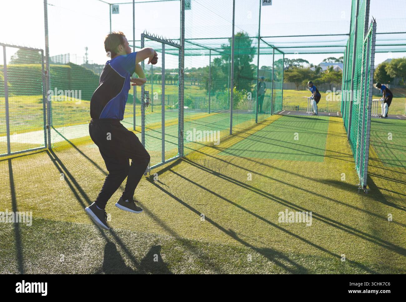 Diverse male teammates practicing bowling and batting with cricket ball ...