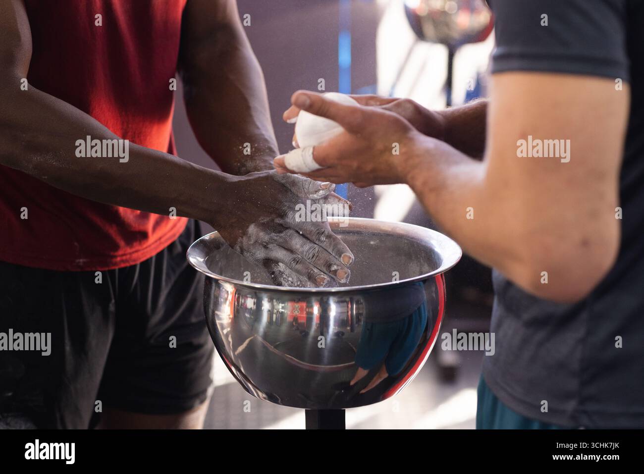 Diverse male training friends rubbing chalk powder into palms at weight ...