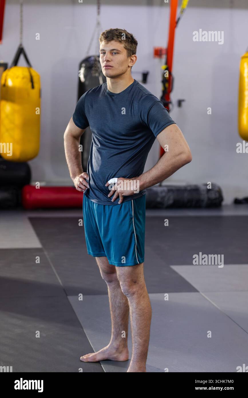 Man wearing athletic clothing training barefoot on mats in boxing gym ...