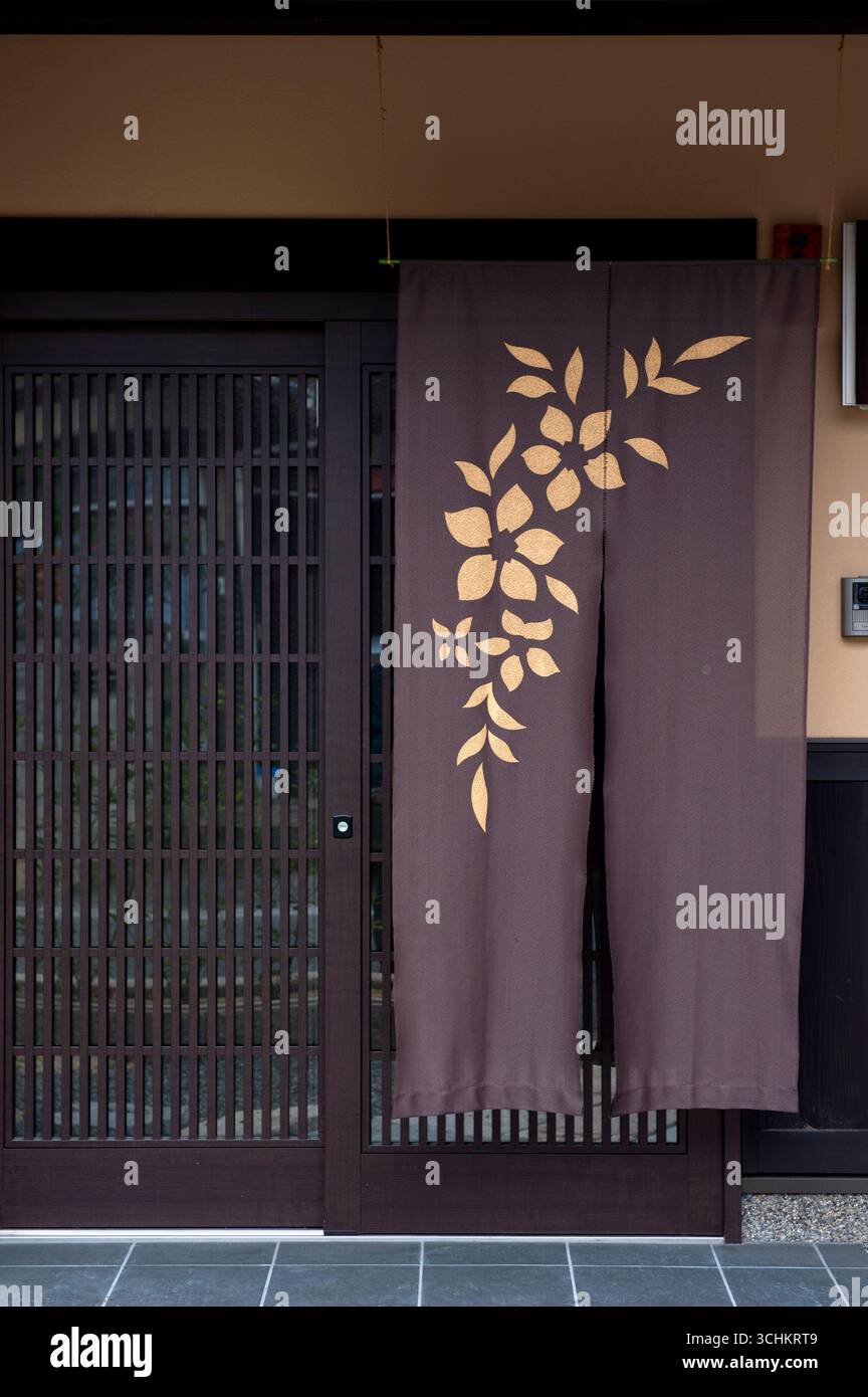 A Japanese "noren" shop curtain with a floral design hangs in the ...