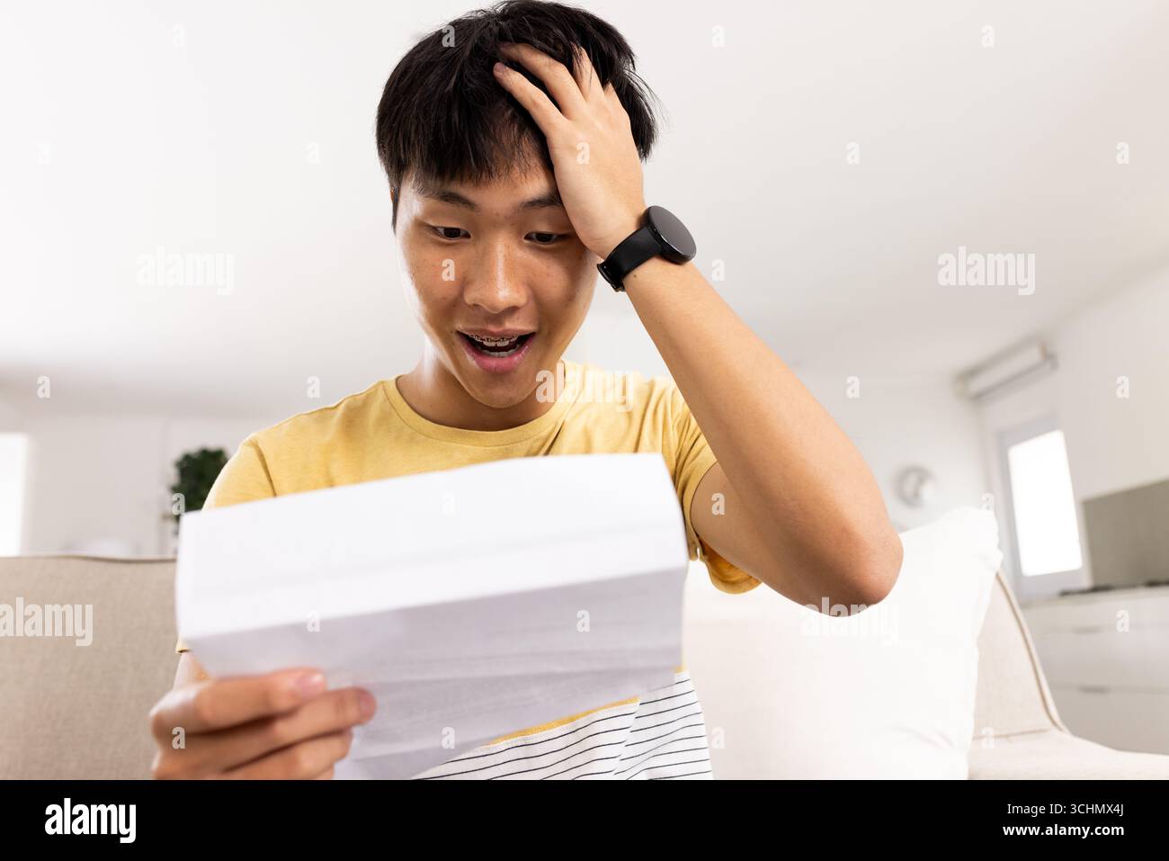 Surprised young man reading letter at home, expressing excitement and ...
