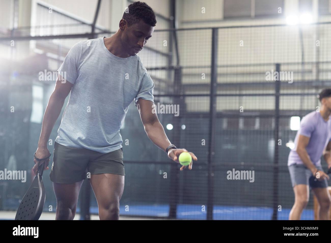 Diverse male friends holding padel rackets, dropping ball and serving ...