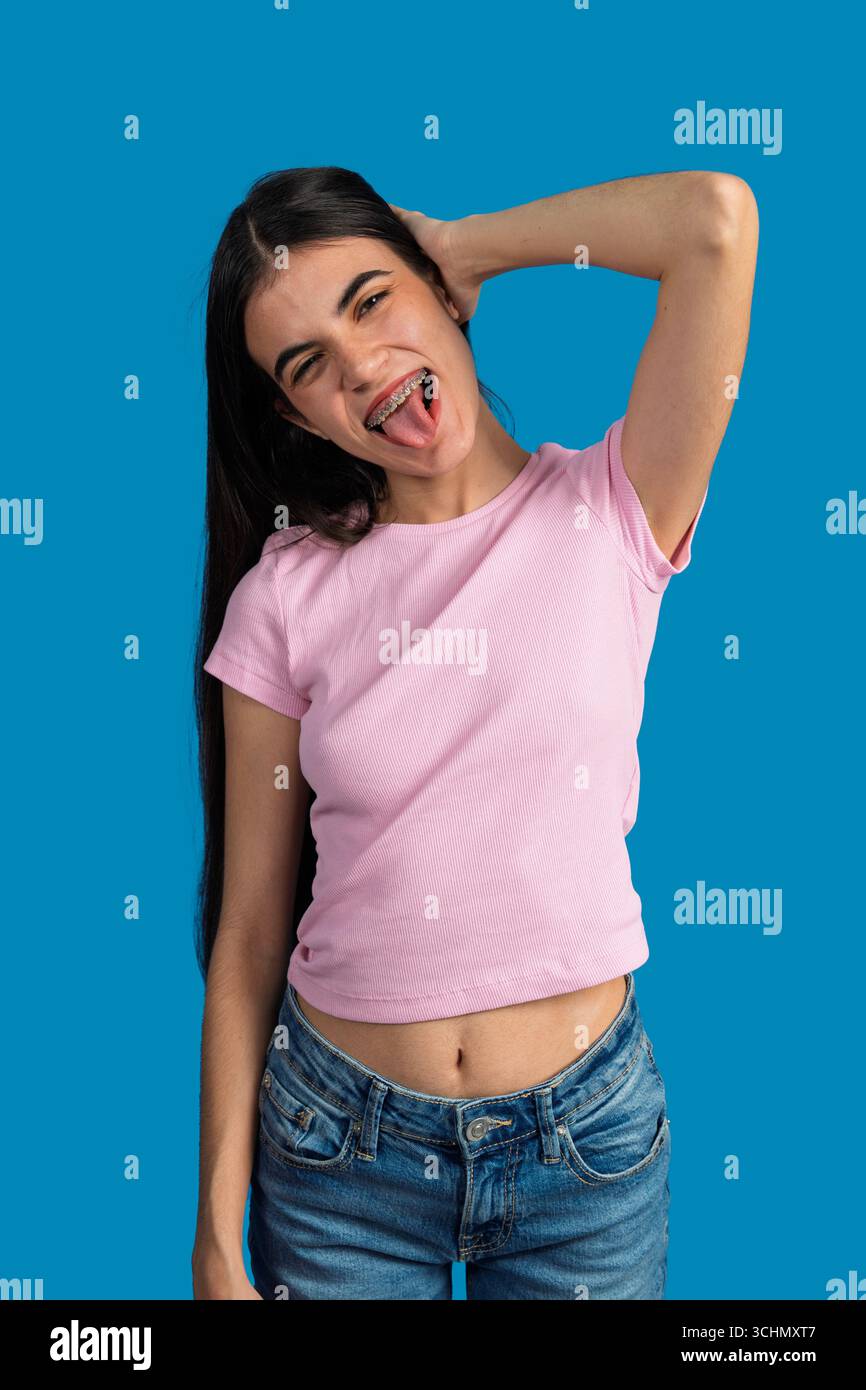 Playful young woman with dental braces sticking out her tongue and ...