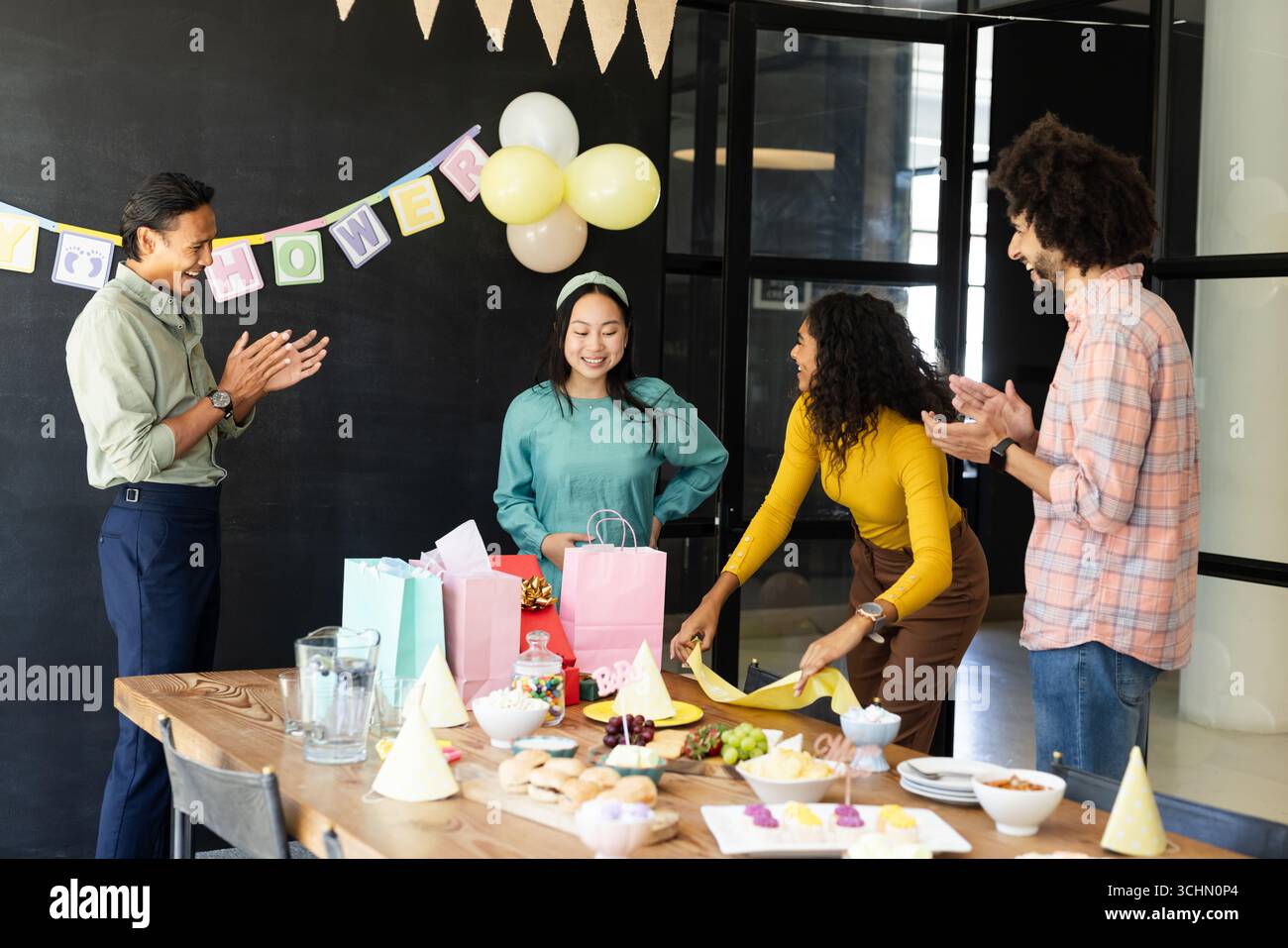 Diverse colleagues celebrating baby shower with gifts and decorations ...