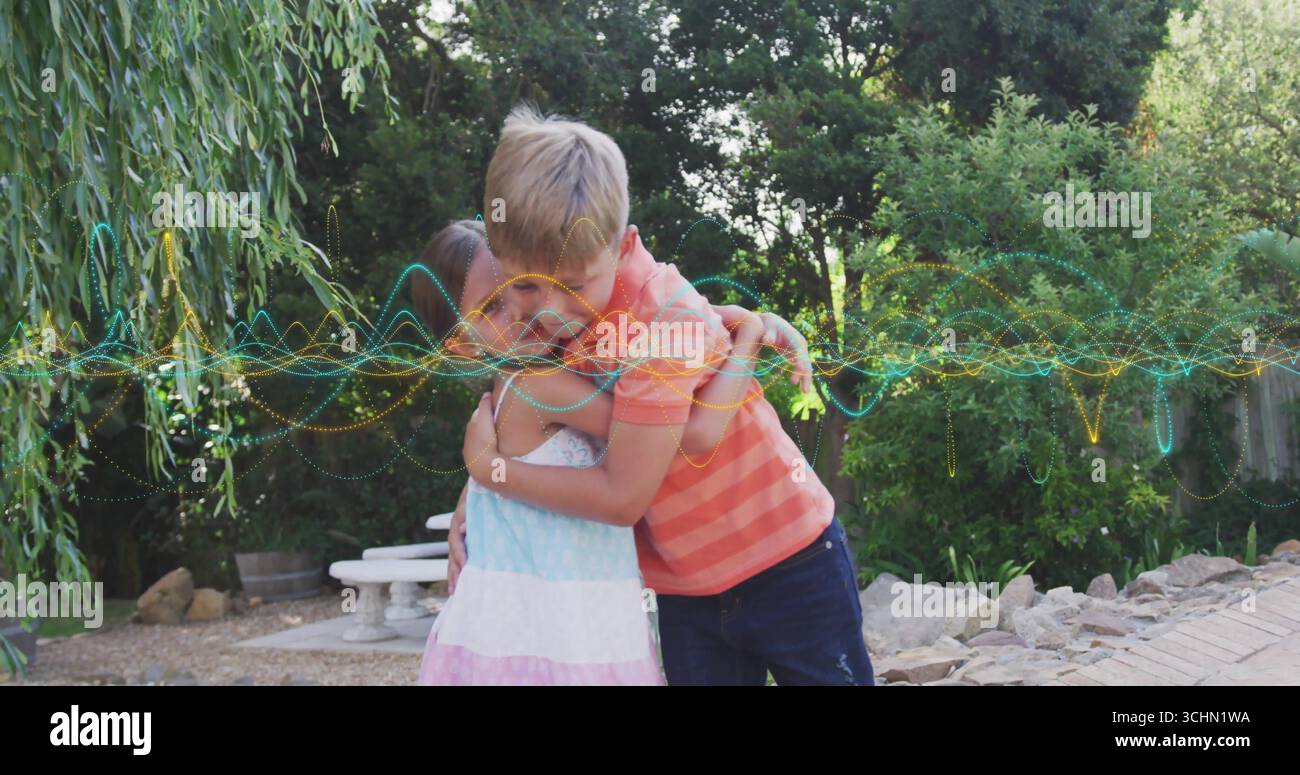 Hugging siblings wearing pastel dress and striped tee in backyard ...