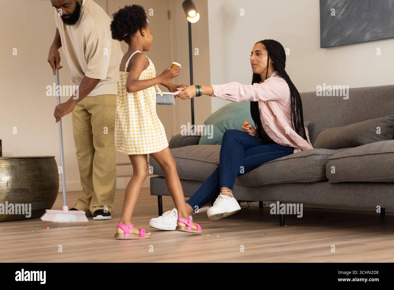 In living room, African American family cleaning, child helping parents ...