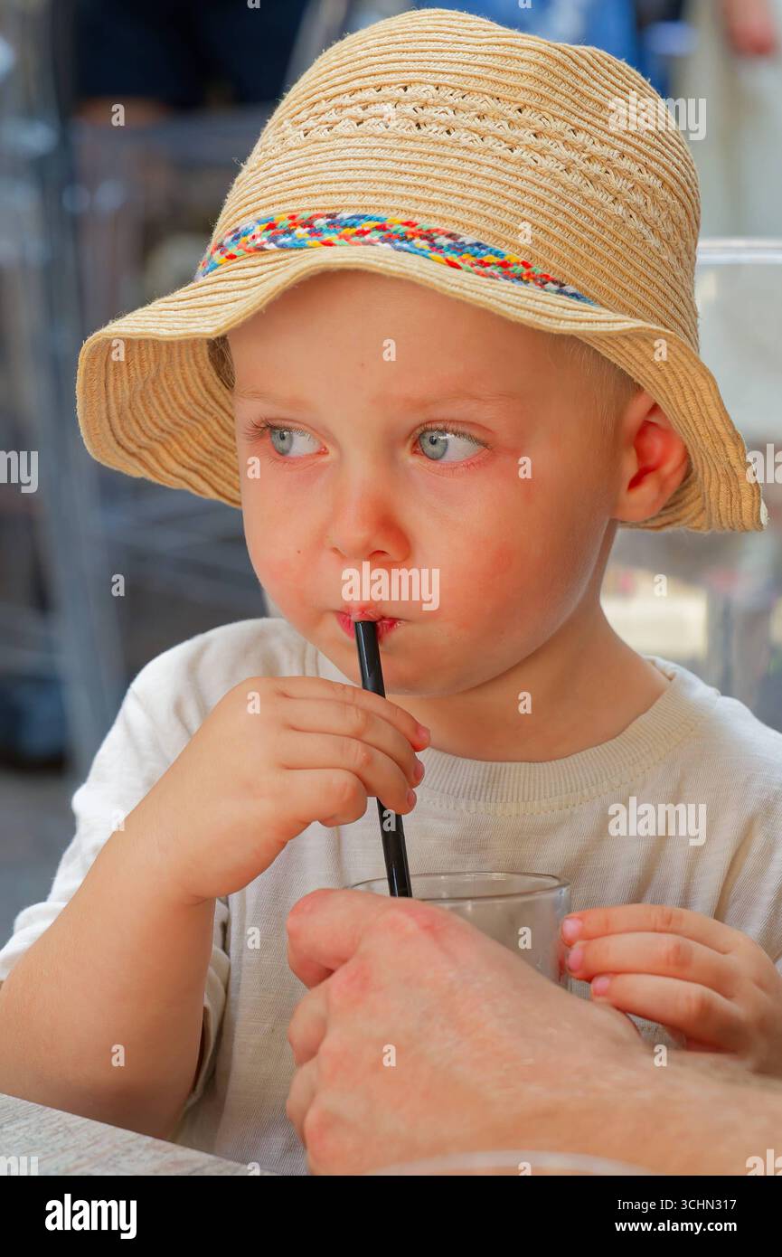 Der große Durst. Der Junge trinkt mit dem Strohhalm sein Getränk ...