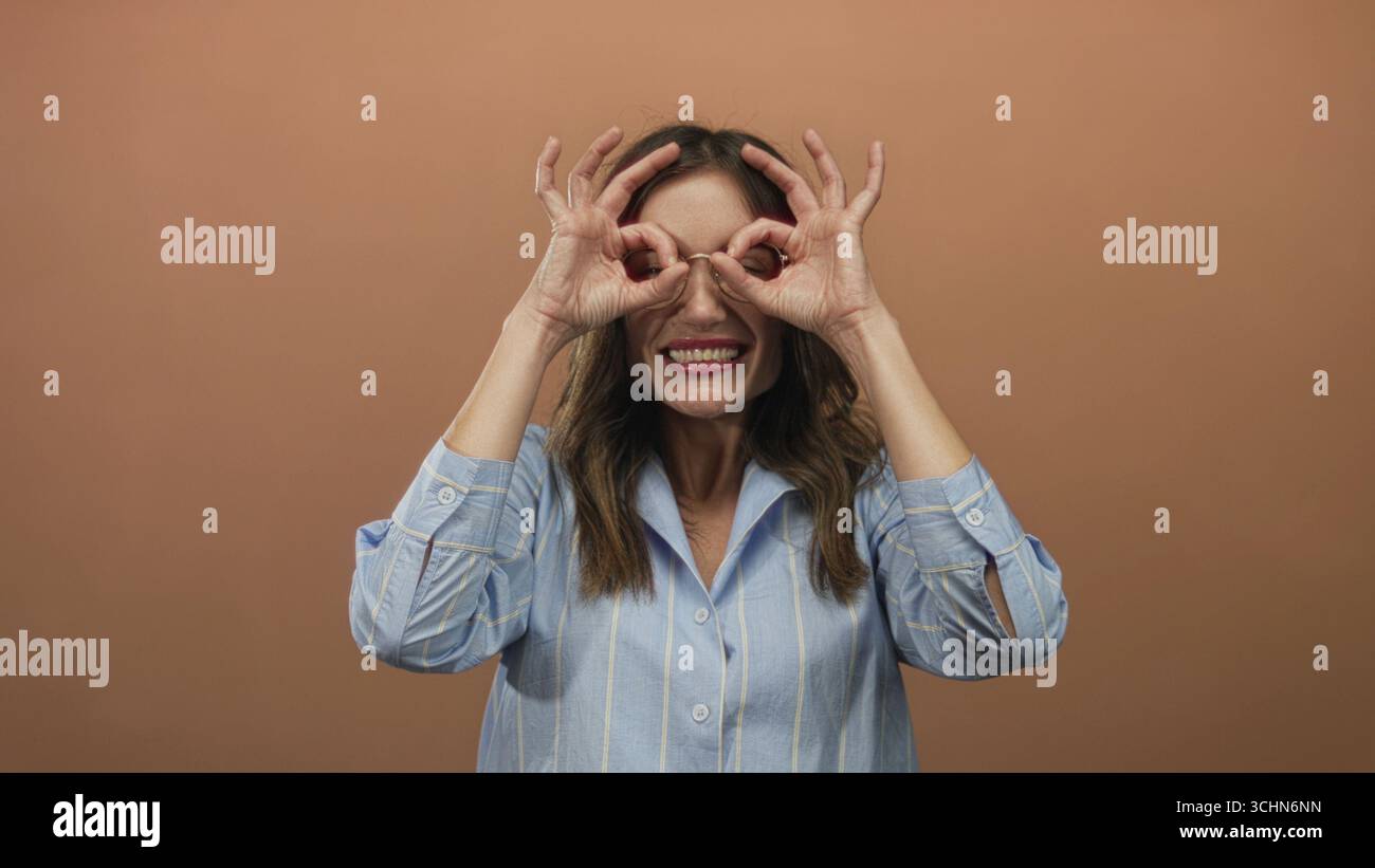 Woman with broad smile frames face with hand binoculars to eyes in ...