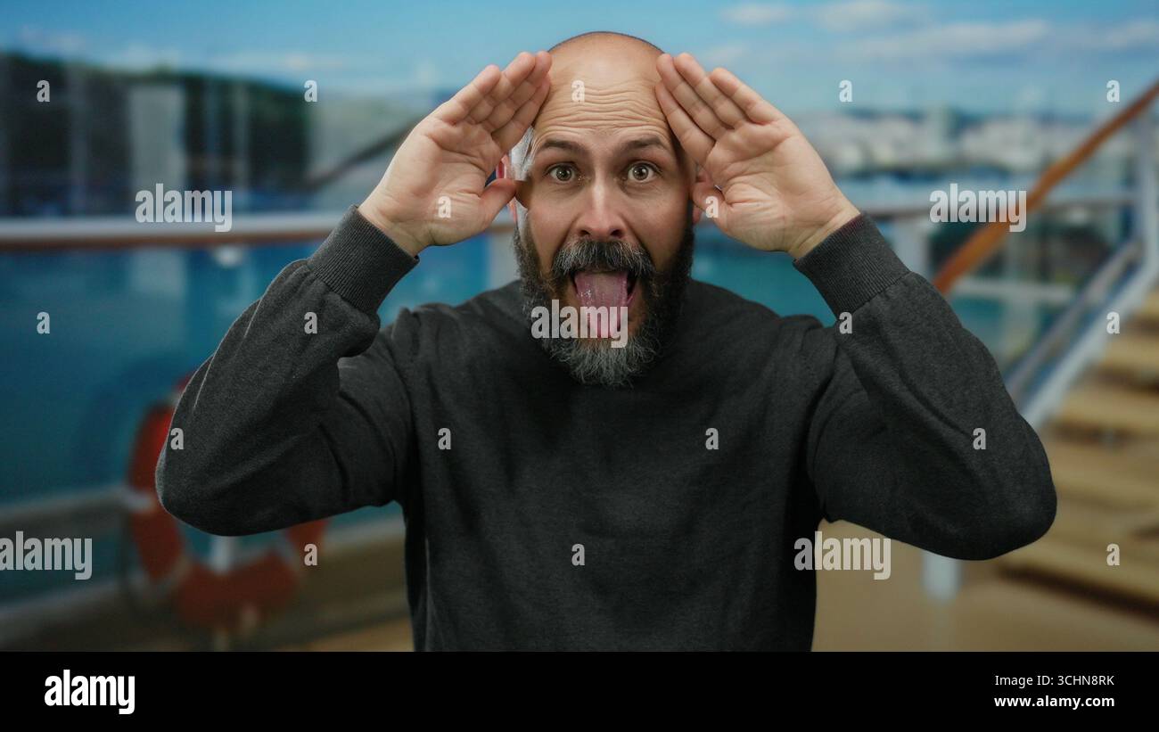 Bald man with beard playfully covers face and makes funny expressions ...