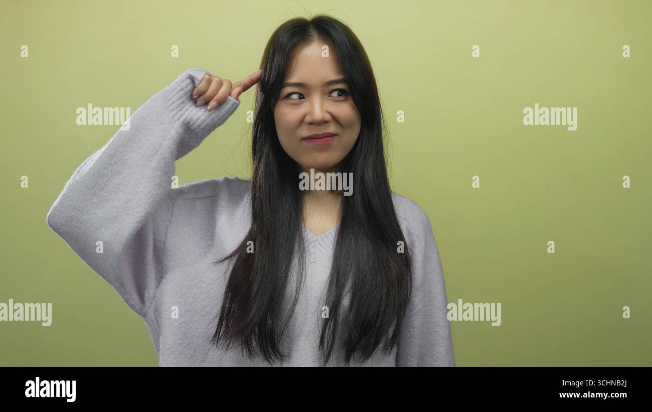 Young chinese woman in a casual sweater making a crazy gesture pointing ...