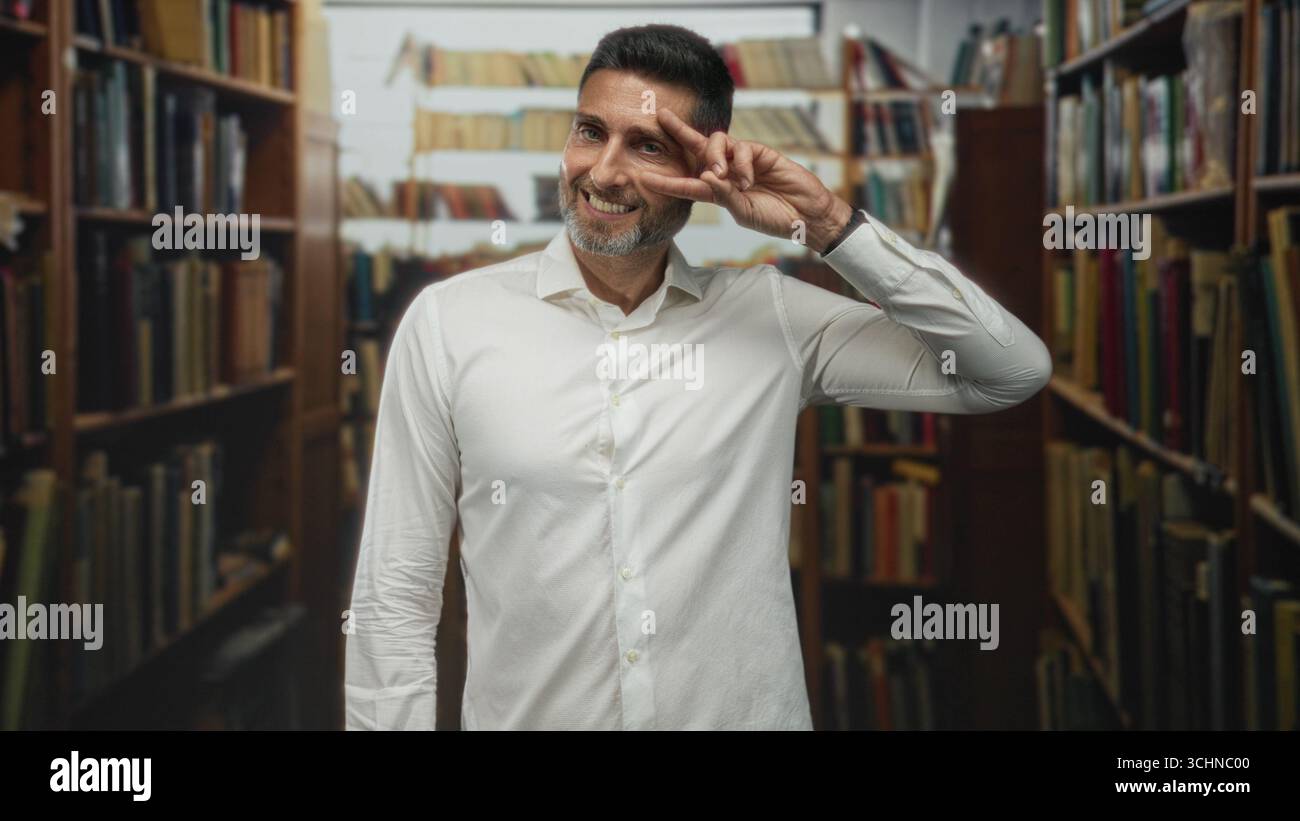 Man with beard and white shirt smiles and shows peace sign while ...
