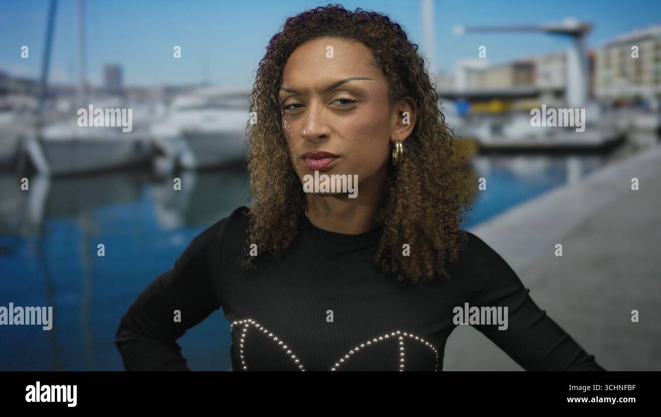 Transgender woman cups hand to ear beside a docked boat at a sunny port ...