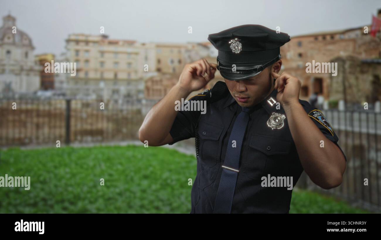 Young man policeman presses hands to ears in ancient roman ruins ...