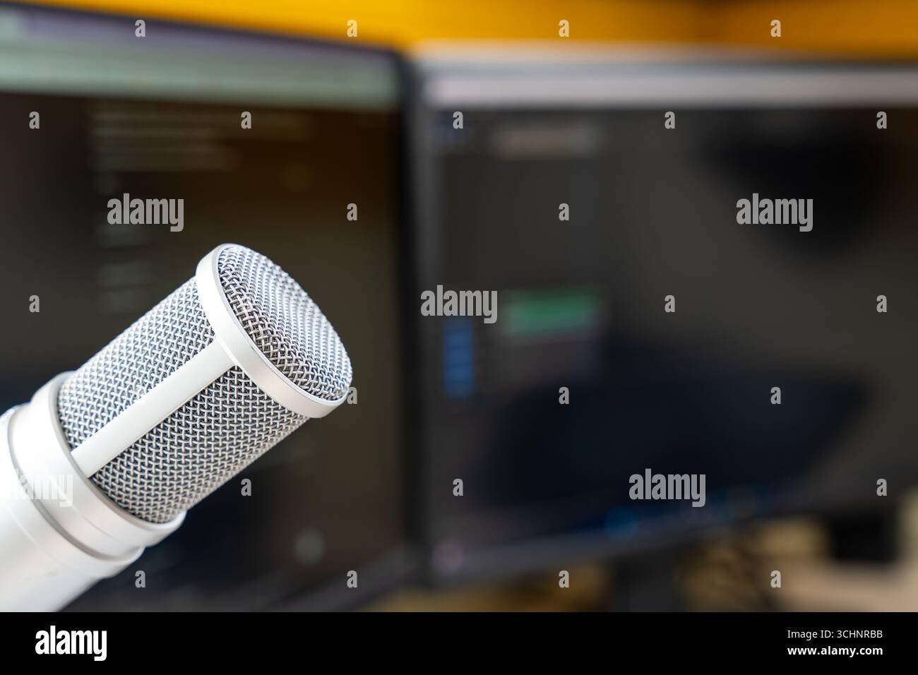 Condenser microphone in studio with blurred background screens showing ...
