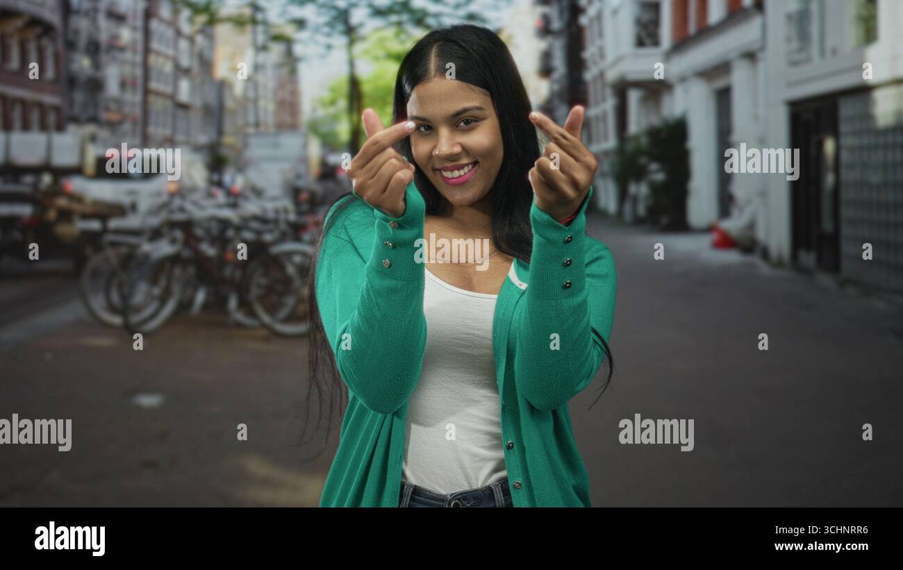 Young latin woman makes finger heart gestures with both hands on busy ...