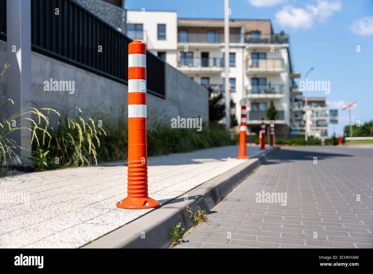 Close-up of orange flexible traffic bollard installed on sidewalk in ...