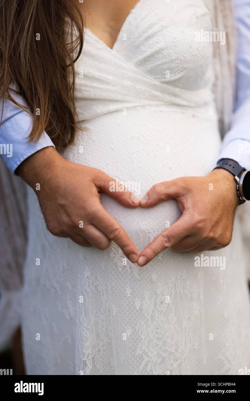 Pregnant woman with hands forming heart shape on her baby bump Stock ...