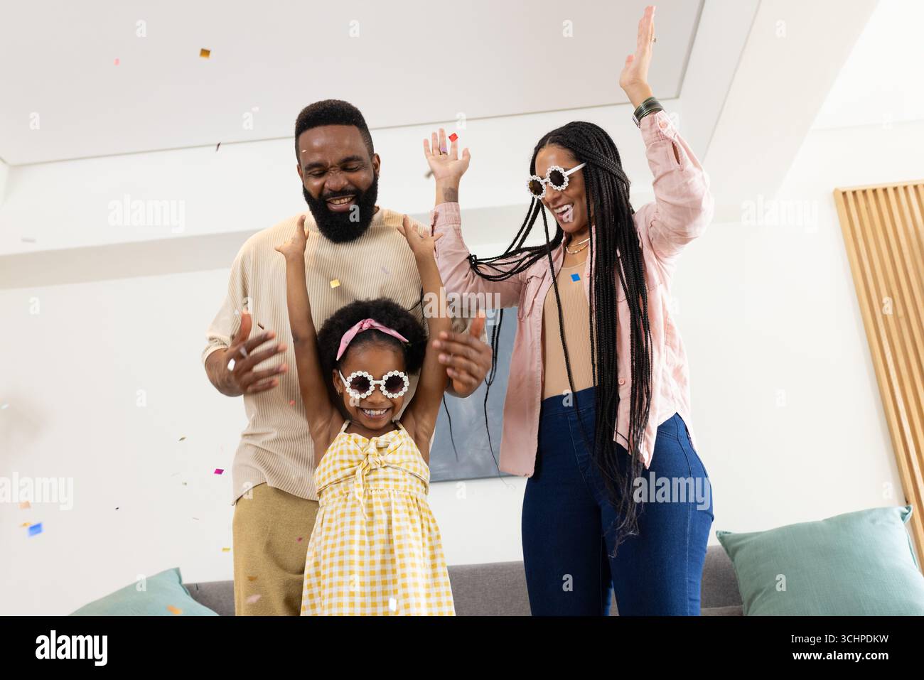 Family celebrating at home, smiling and throwing confetti with joy ...