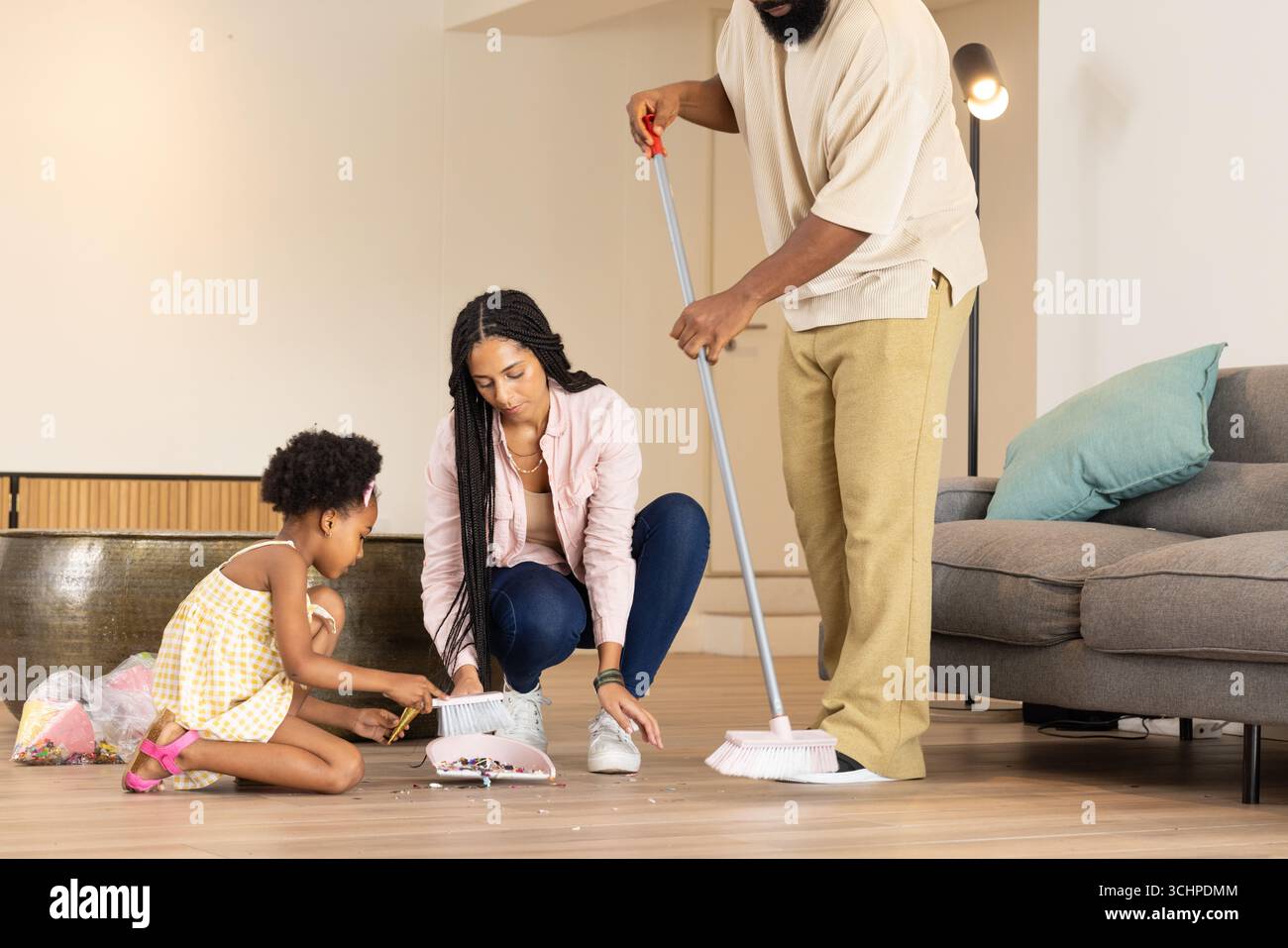 Family cleaning living room together, sweeping floor and picking up ...