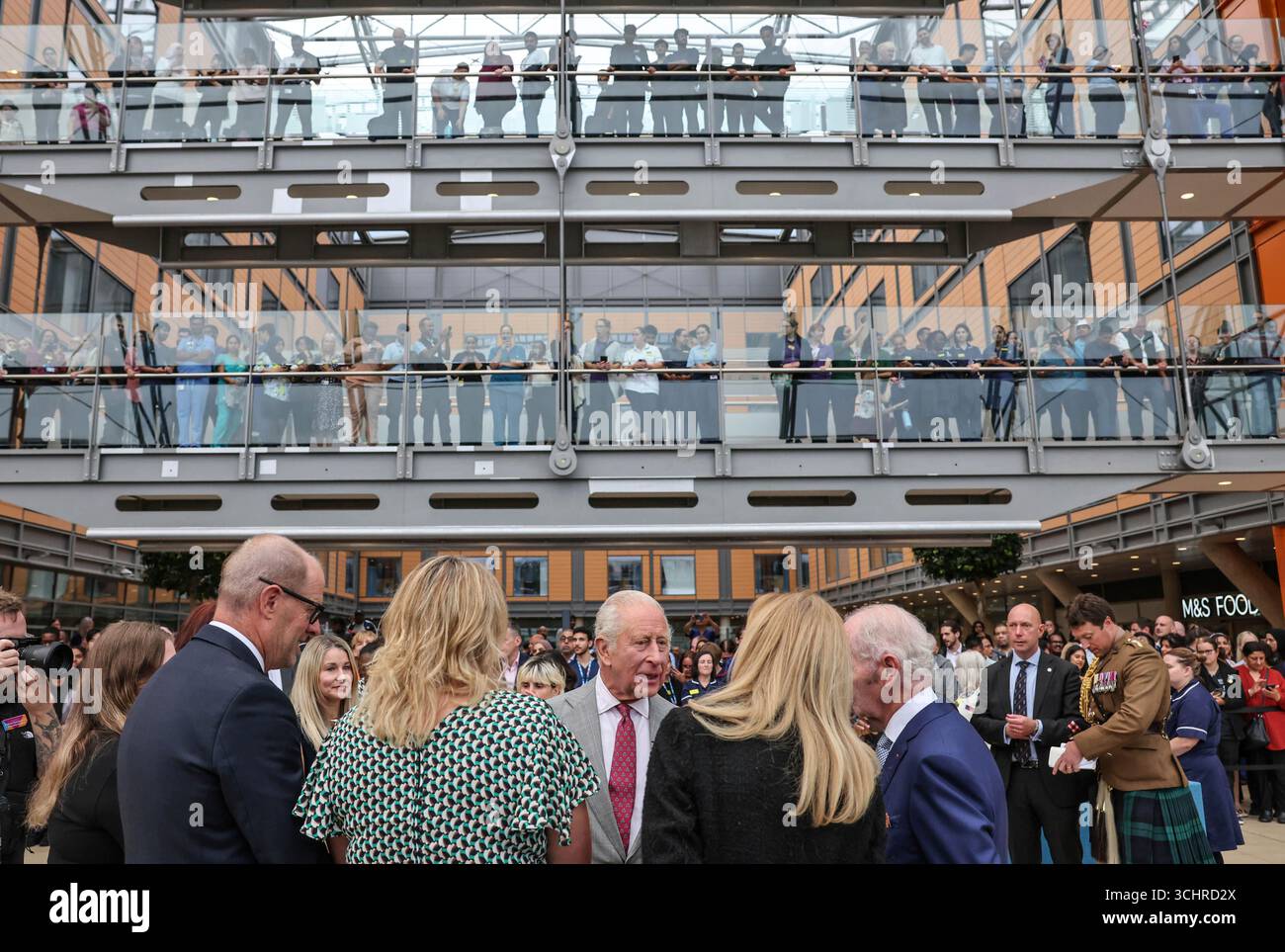 Staff, visitors and patients line the walkways to see Britain's King ...
