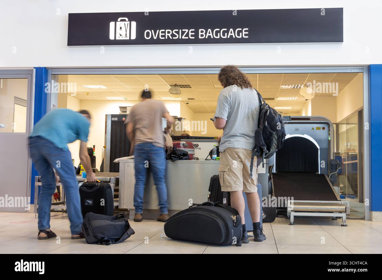 Passengers with luggage queue in front of the airport's oversized ...