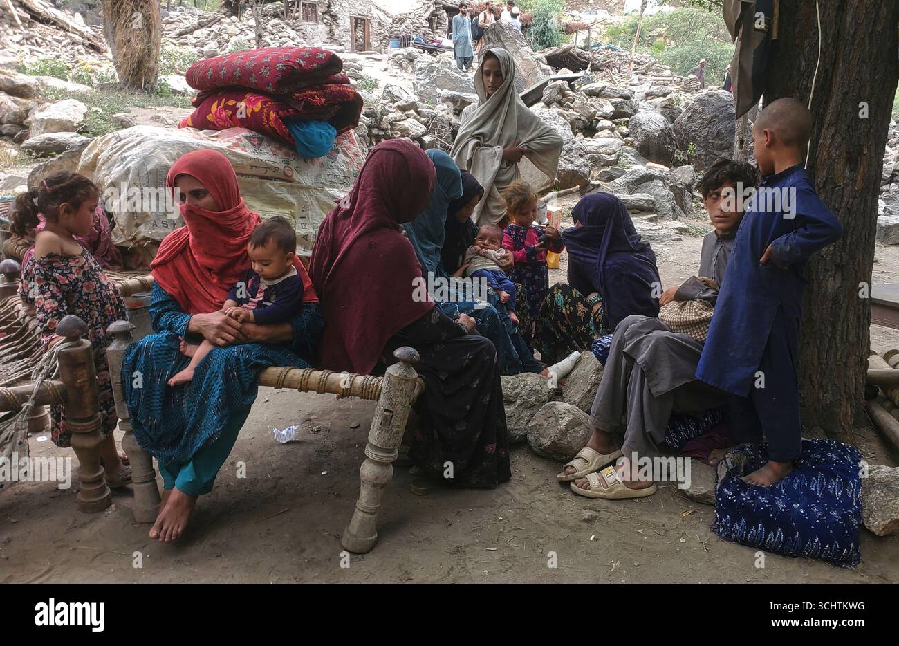 Displaced Afghan families gather under trees with their belongings ...
