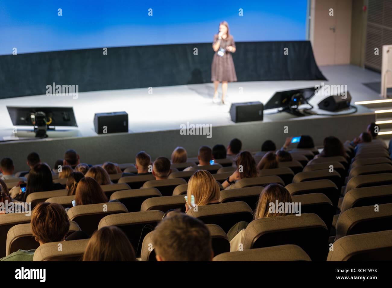 Conference speaker presenting to audience in auditorium on professional ...