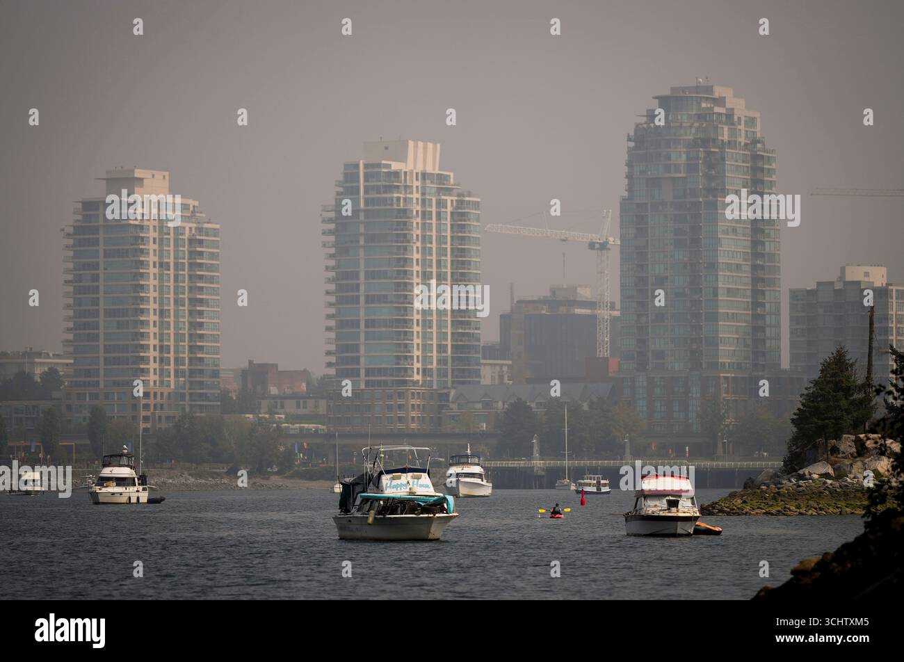 A woman paddles a kayak on False Creek as smoke from wildfires burning ...