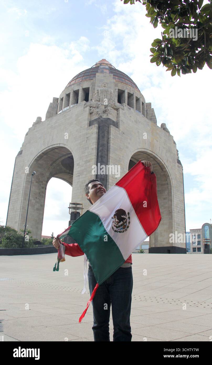 Dark-skinned Mexican man proudly displays the Mexican flag in downtown ...