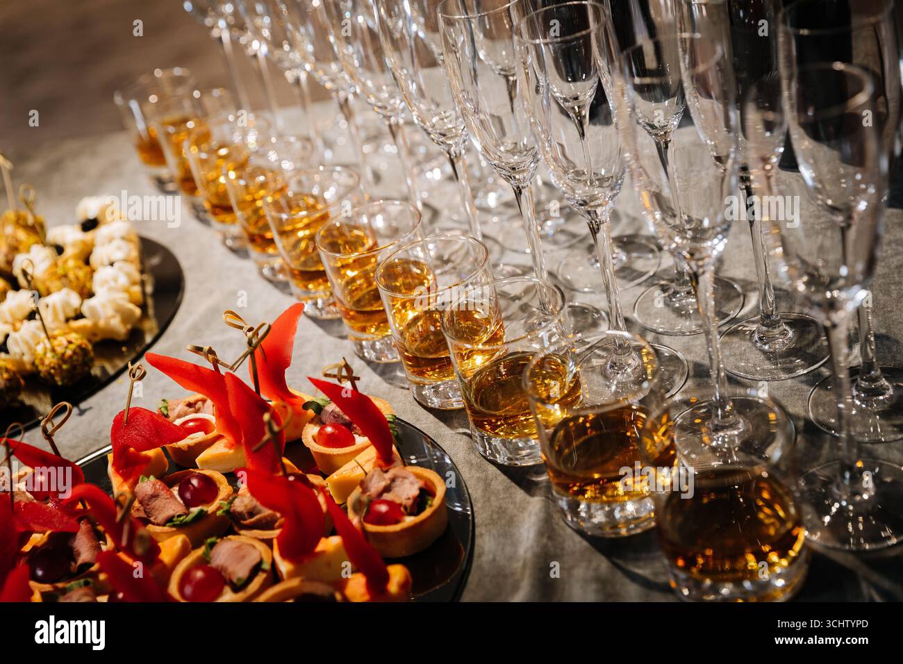Elegant buffet with whiskey shots, canapes, and champagne glasses at a ...