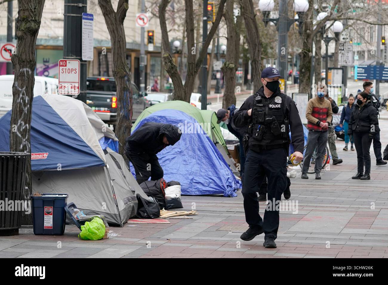 FILE - A Seattle police officer walks past tents used by people ...